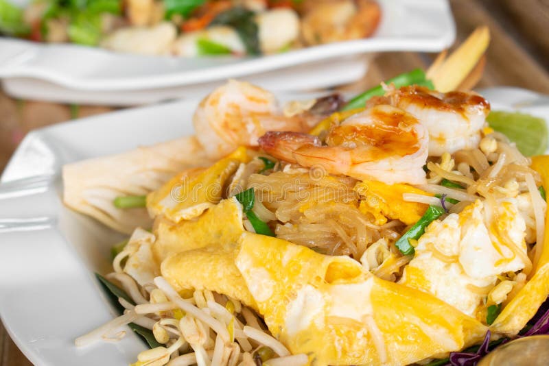 Omelet Wraped Pad Thai with Fresh Shrimp in White Dish on Bamboo Table ...