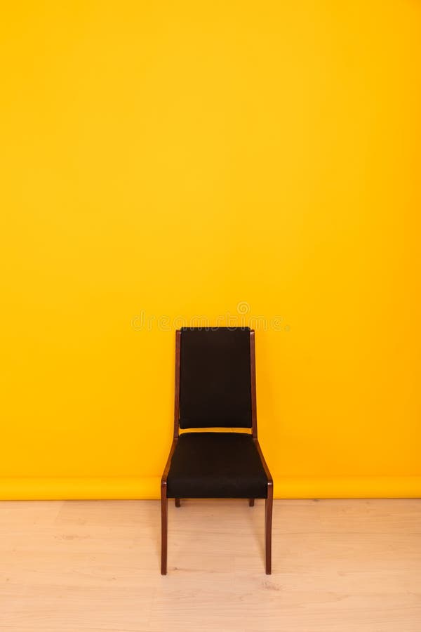 One Black Chair Against a Yellow Wall Stock Image - Image of wall ...