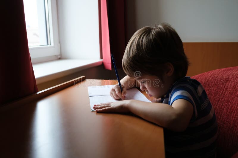 One Cute Kid is Sitting at the Table and Doing Homework. the Child ...