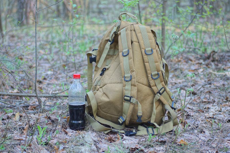 One Full Brown Army Backpack and a Plastic Bottle with a Black Drink ...