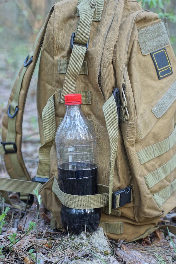 One Full Brown Army Backpack and a Plastic Bottle with a Black Drink in ...