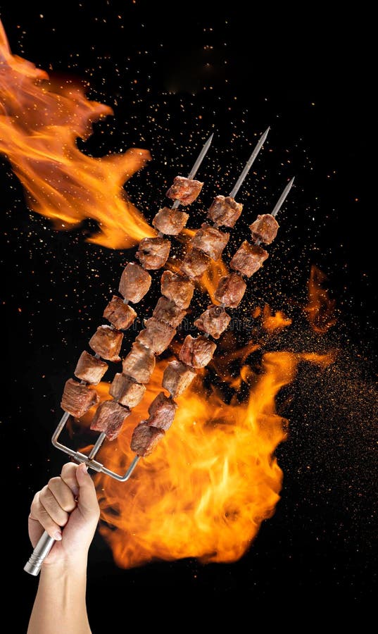 One Hand Holds Three Skewers of Meat, and There is a Jet of Fire in the ... One Hand Holds Three Skewers of Meat, and There is a Jet of Fire in the ...