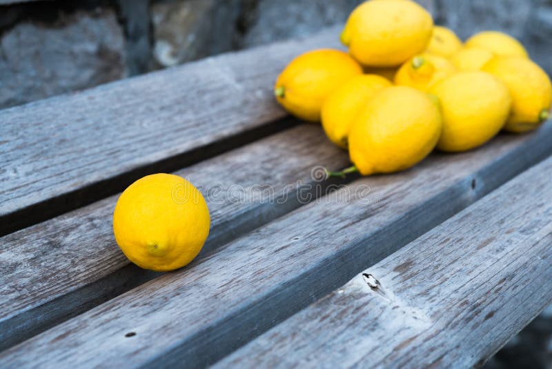 One Lemon on Wooden Bench and Group of Lemons Behind Stock Photo ...