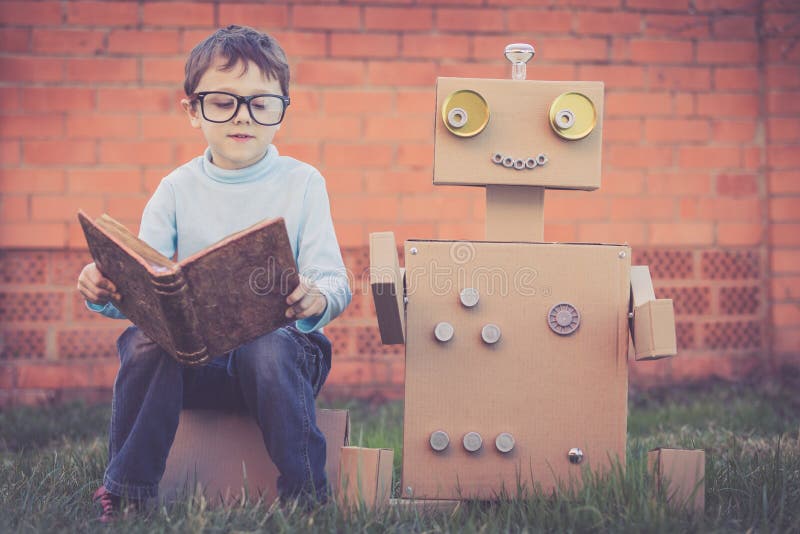 One Little Boy Reading To Robot from Cardboard Boxes Outdoors. Stock ...