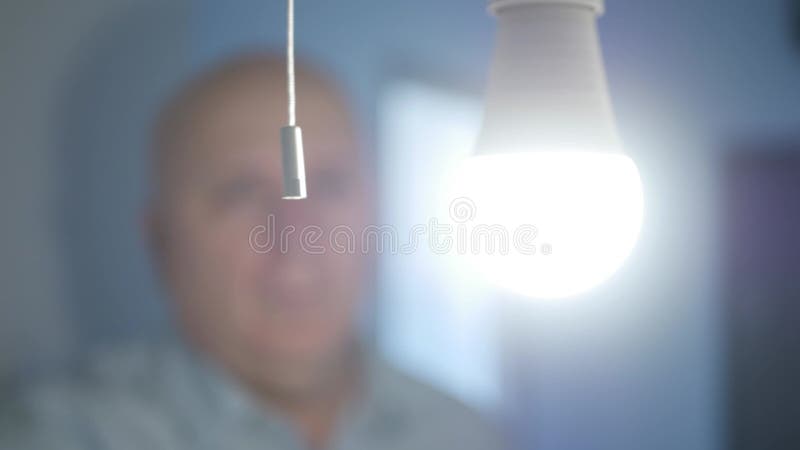 One Person Pull the Switch Cord and Turns on the Light Bulb in a Dark ...