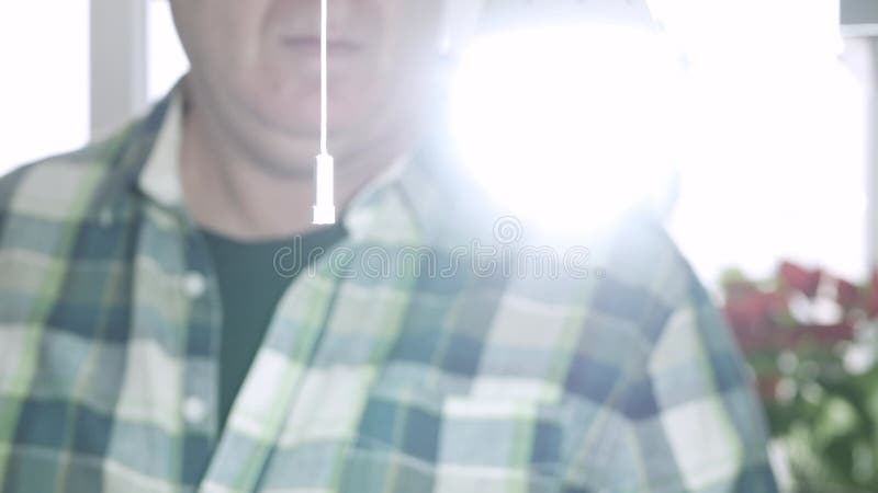 One Person Pull the Switch Cord and Turns on the Light Bulb in a Dark ...