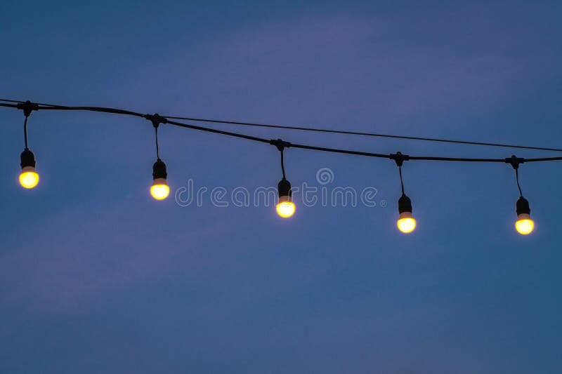 One Row of Warm White Light Bulbs Turn on with the Sky in the ...