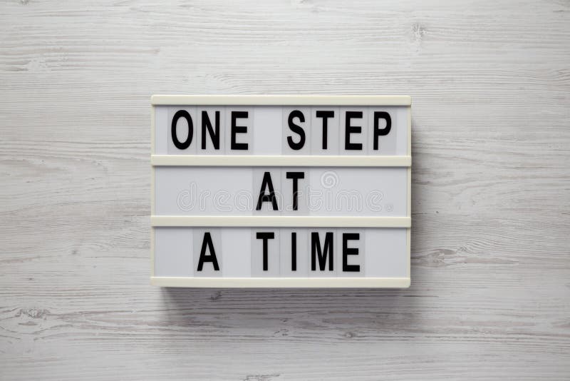 `One Step at a Time` on a Lightbox on a White Wooden Surface, Top View ...