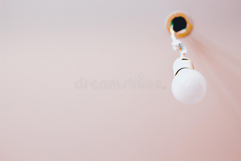 One White Light Bulb is Hanging on the Wire Under the White Ceiling ...