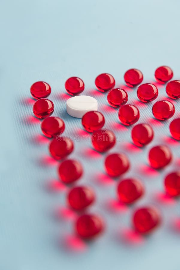 One White Round Tablet In A Grid Of Red Capsules Stock Photo - Image of ...