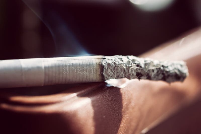 Smoldering Cigarette in a Man`s Hand in Nature Against the Backdrop of ...