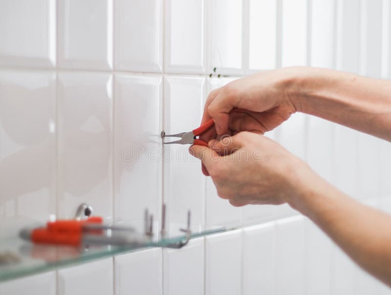 A Young Man Pulls Out a Dowel from the Wall Using Pliers. Stock Photo ...