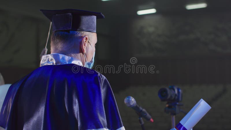University Lecturer in Academic Clothes and Hat is Presenting Diplomas ...