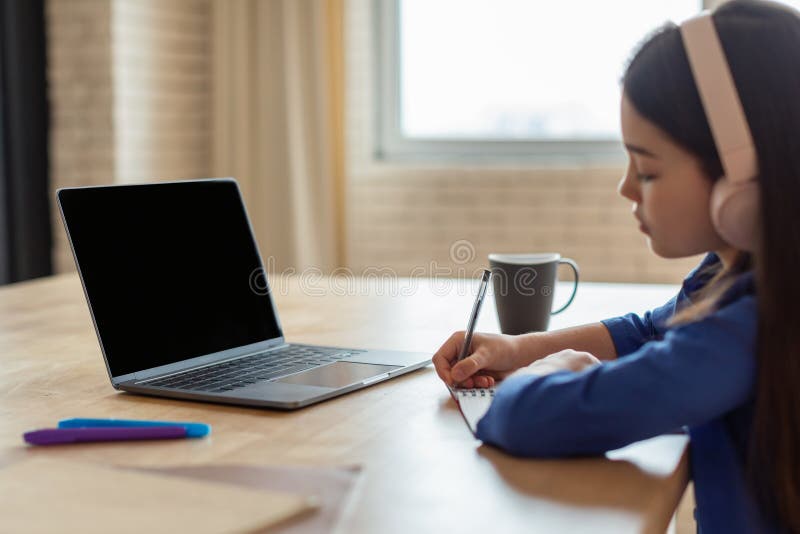 Schoolgirl with Earphones Taking Notes at Laptop Computer at Home Stock ...
