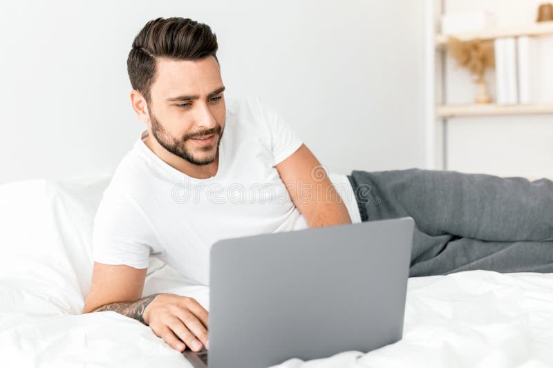 Always Online. Positive Young Man Working on Laptop Distantly, Lying on ...