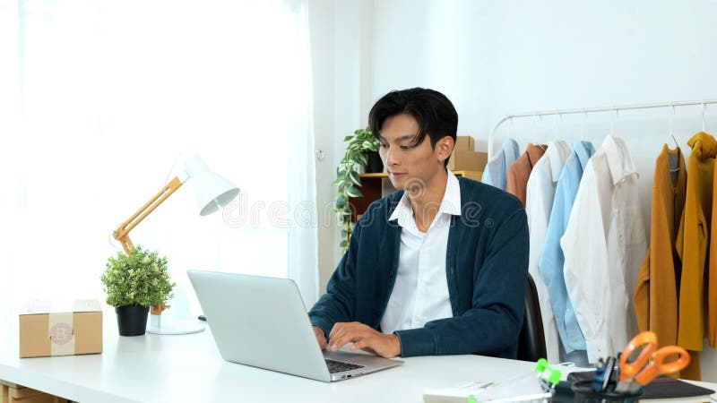 An Online Store Owner Managing Tasks on a Laptop in a Bright Office ...