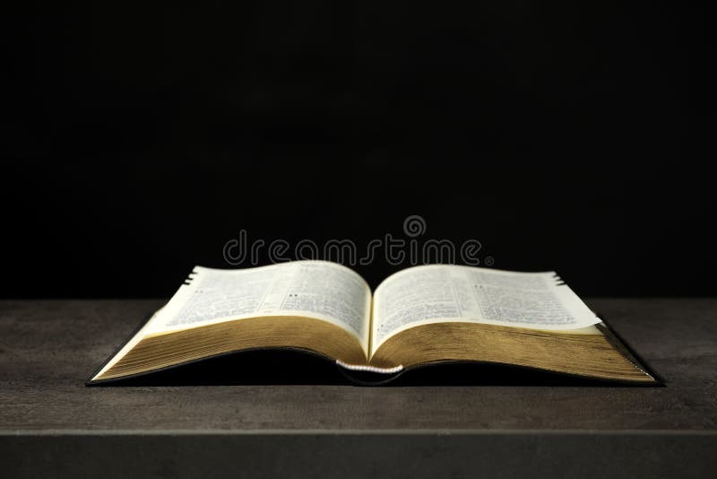 Open Bible on Grey Table Against Black Background Stock Image - Image ...