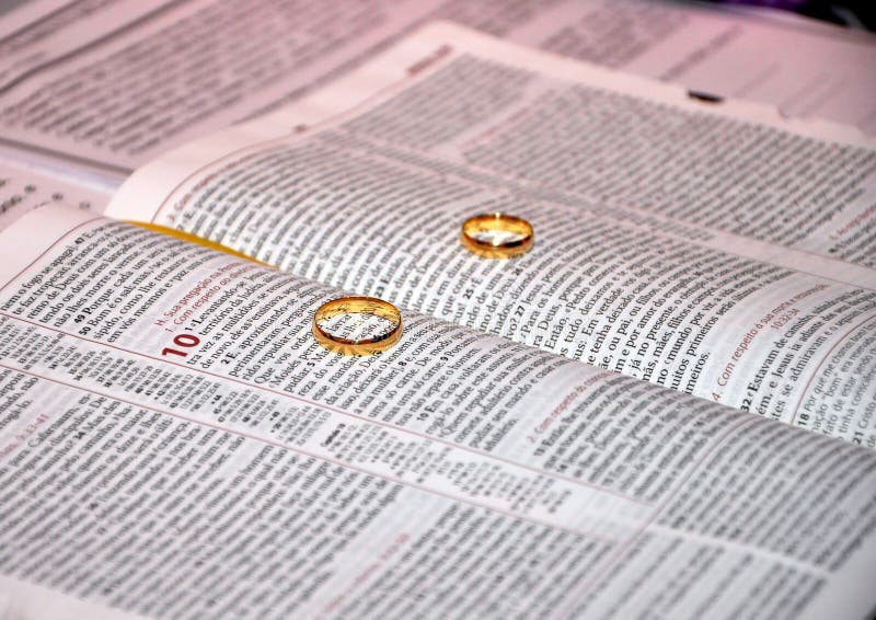 The Open Bible with the Holy Scriptures with the Wedding Rings on the ...