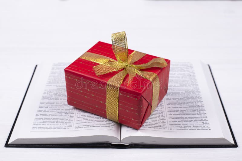 An Open Bible on the Table. a Gift on a Book. a Red Gift-wrapped Box ...