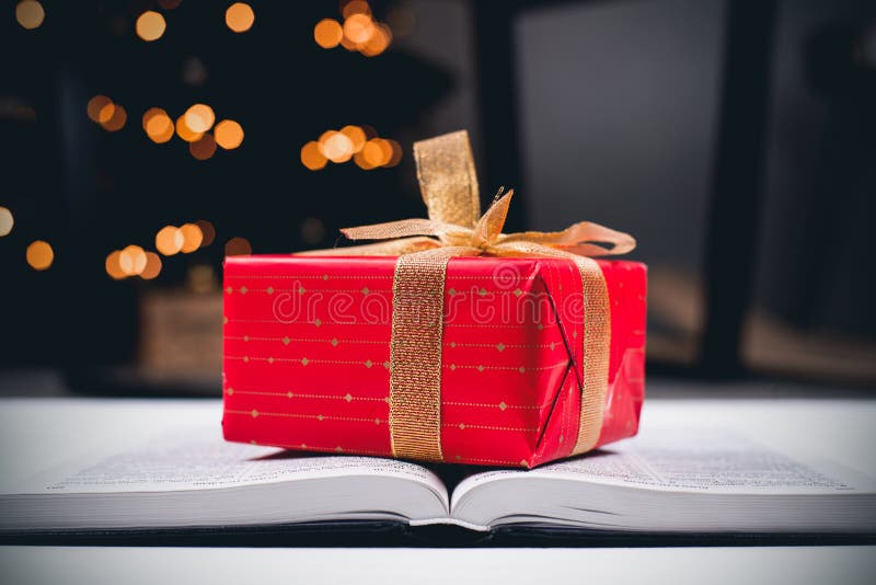An Open Bible on the Table. a Gift on a Book. a Red Gift-wrapped Box ...