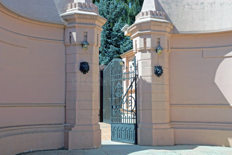 Open Black Iron Gates with Wrought Pattern and Brown Concrete Fence ...