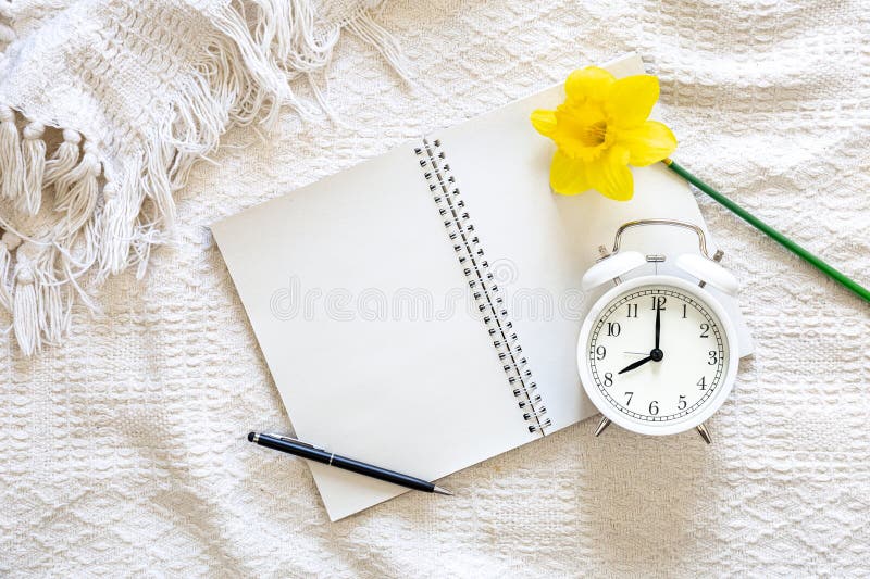 Open Blank Notebook, Yellow Flower and White Alarm Clock in White Bed ...