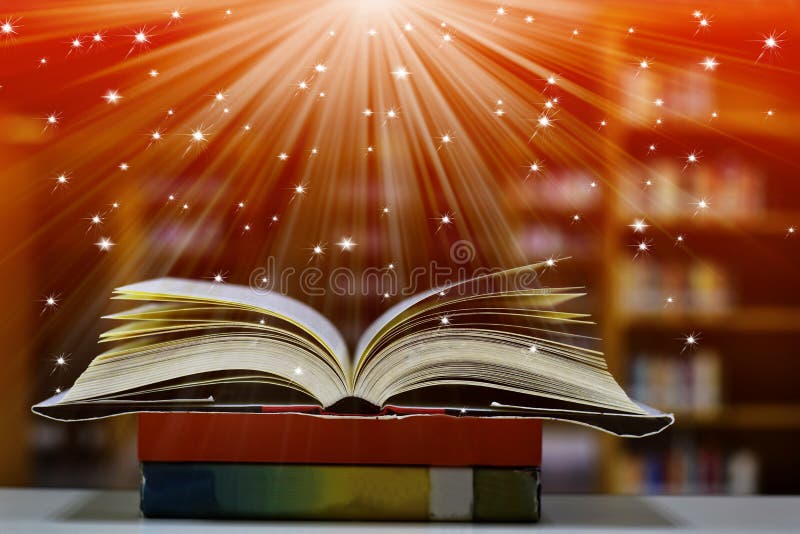 Open Book with Abstract Magic Bright Light on Wooden Table and Blurred ...