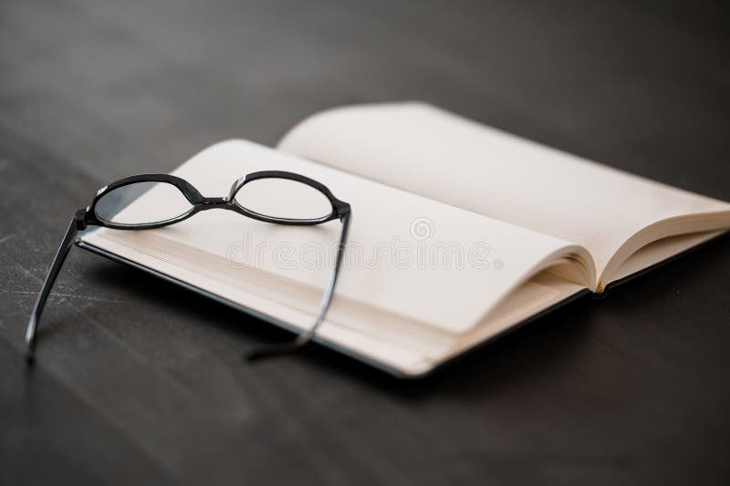 Open Book with Glasses on a Dark Wooden Table, Representing Reading or ...