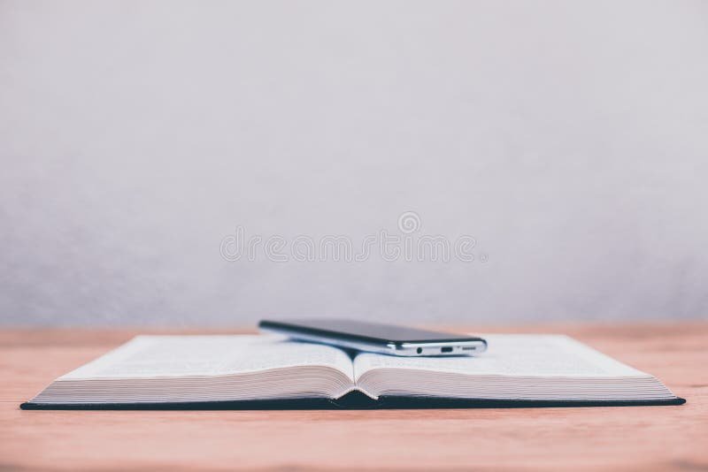 The Open Book of the Holy Bible. the Phone is on the Book. on the Table ...