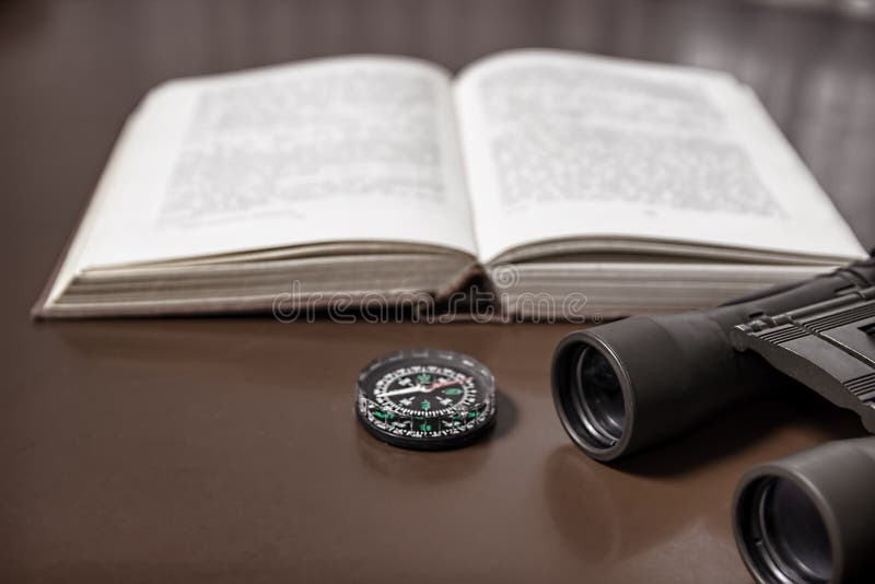 An Open Book on the Table, with a Pair of Binoculars and a Compass ...