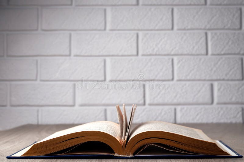 An Open Book with Torn Pages on a Table Against a Wall of White ...