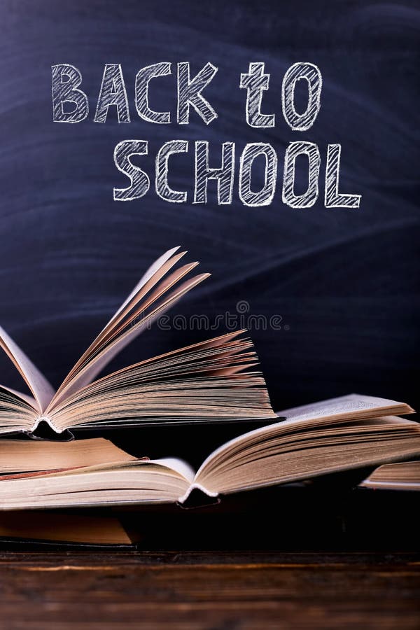 Open Books are a Stack on the Desk, Against the Background of a Chalk ...