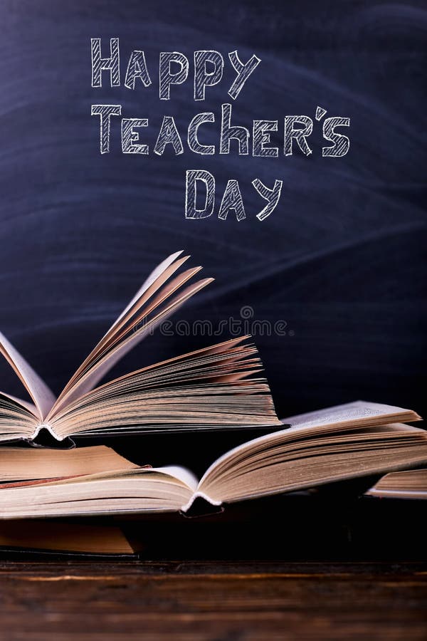 Open Books are a Stack on the Desk, Against the Background of a Chalk ...