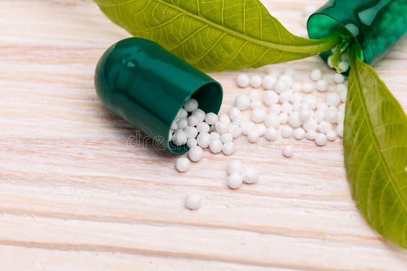 Open Capsule with Small White Specs and Green Leaf Stock Photo - Image ...