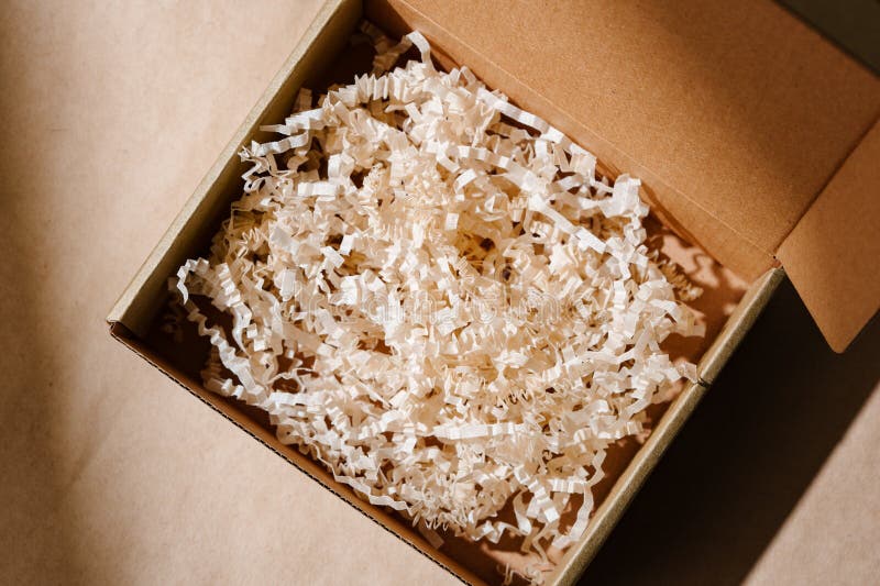 Open Cardboard Box with Shredded Paper Packaging Resting on a Light ...