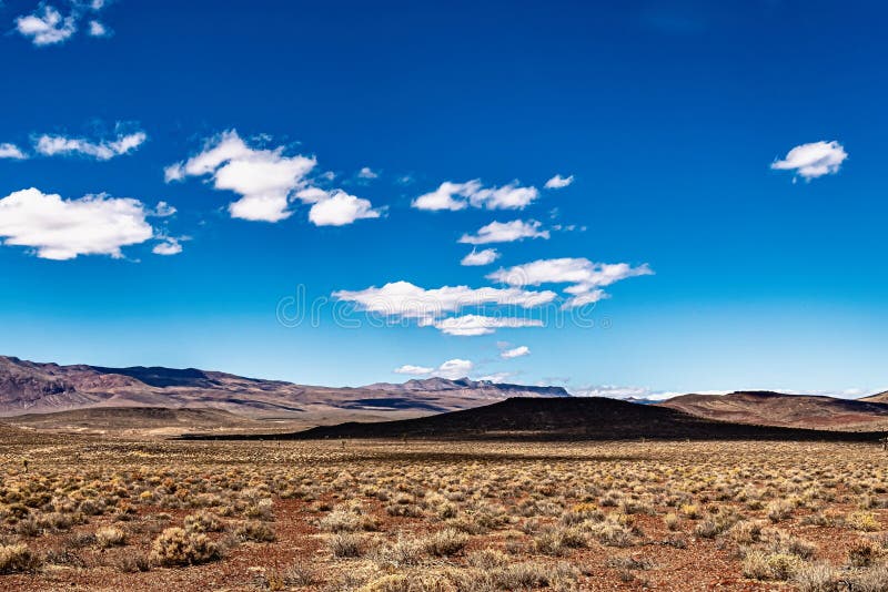 Open Desert Field with Mountains and a Cloudy Blue Sky in the ...