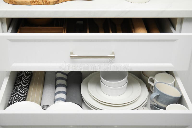 Open Drawers of Kitchen Cabinet with Different Dishware and Towels ...