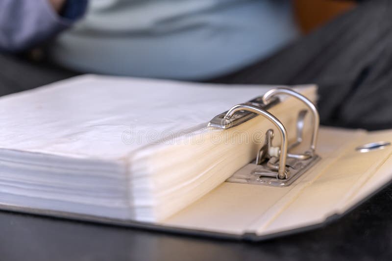 Open Gray File Folder with Metal Binder. Papers are on a Black Desk ...