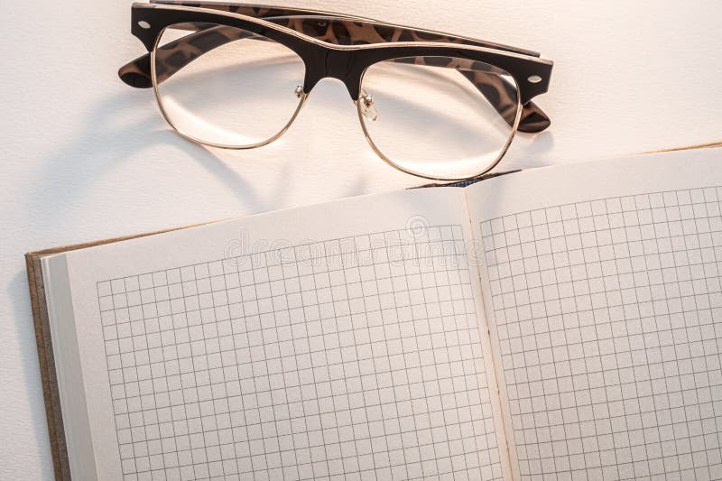 Open Grid Notebook with Brown Glasses on White Table Stock Image ...