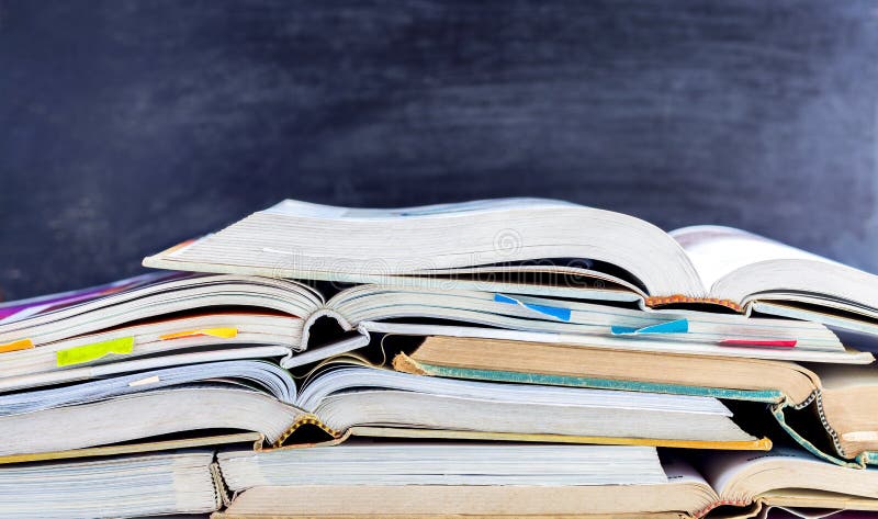 Open Hardback and Textbook Stacked on the Table on Blackboard Ba Stock ...