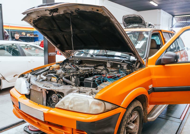 Open Hood of Orange Car Undergoing Electrical Diagnostics in Auto ...