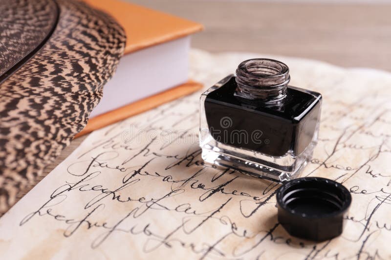 Open Inkwell, Feather, Book and Vintage Parchment with Text on Table ...