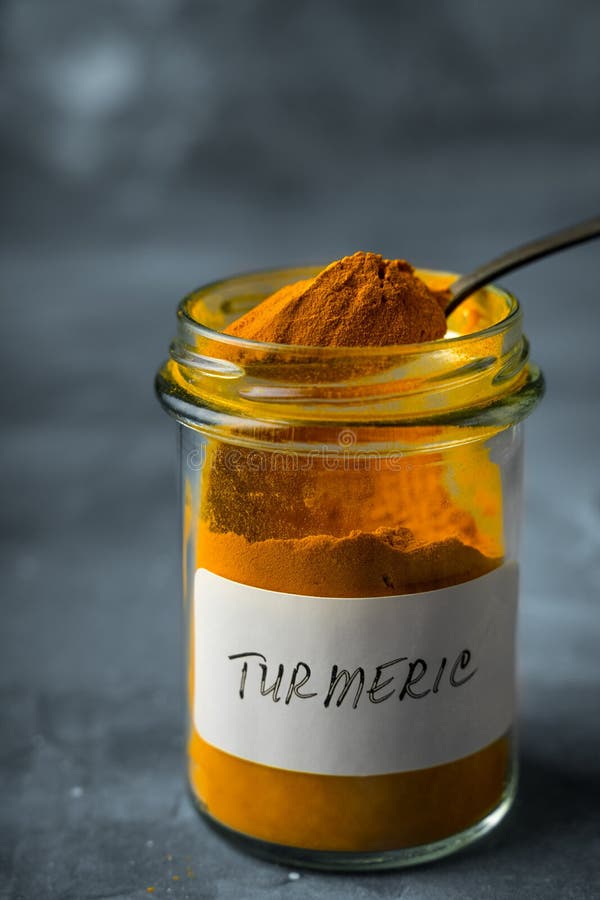 Open Jar of Ground Turmeric with a Spoon on Gray Background, Closeup ...