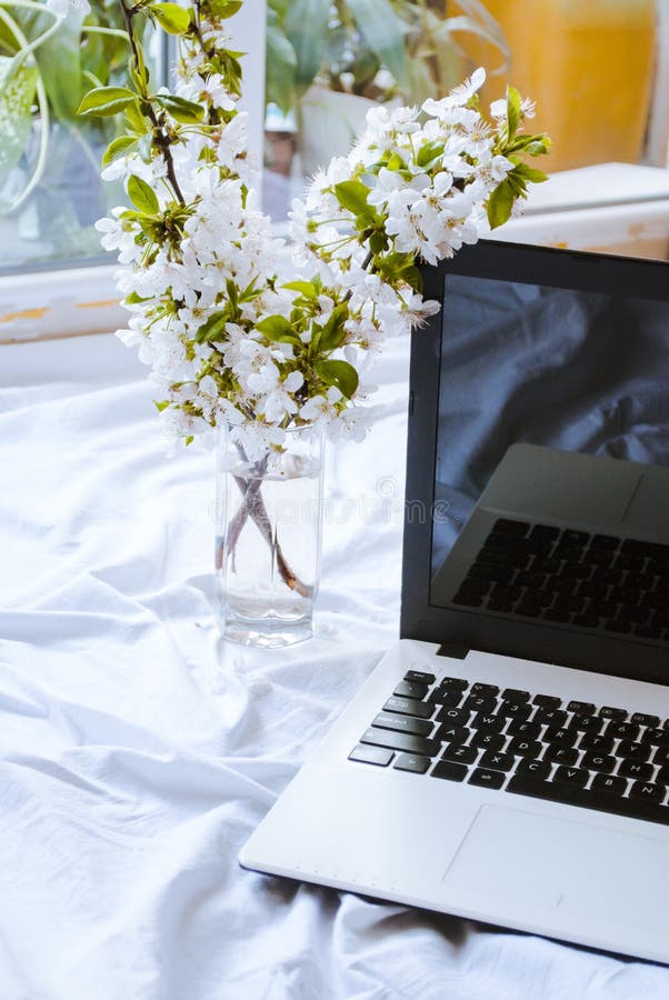 Open Laptop on the Bed and Spring Flowers. Work at Home. Home Office ...