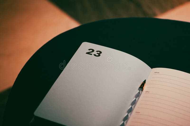 An Open Pad with a Date 23 is Lying on Dark Round Table Top View. a ...