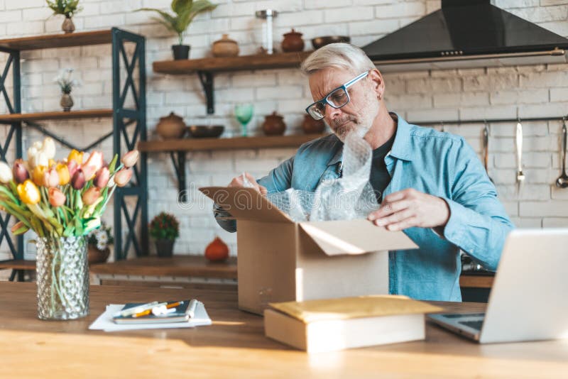 Open the Parcel at Home. an Elderly Man Unpacks an Online Order Stock ...