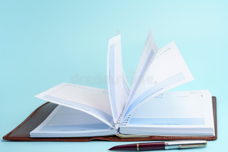Open Planner with Flipping Pages and a Pen on a Blue Background Stock ...