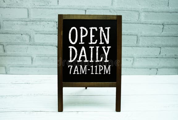 Open daily 7am-11pm Sign with Blackboard on White Brick Background ...