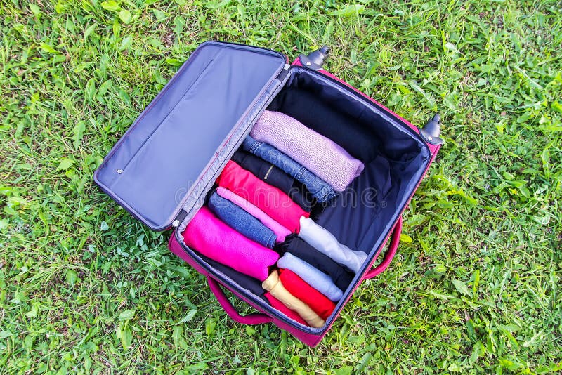 Open Suitcase on the Green Grass with Different Clothes Folded ...