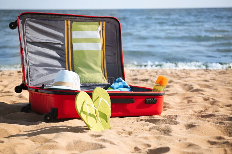 Open Suitcase with Stylish Beach Accessories on Sand Near Sea Stock ...